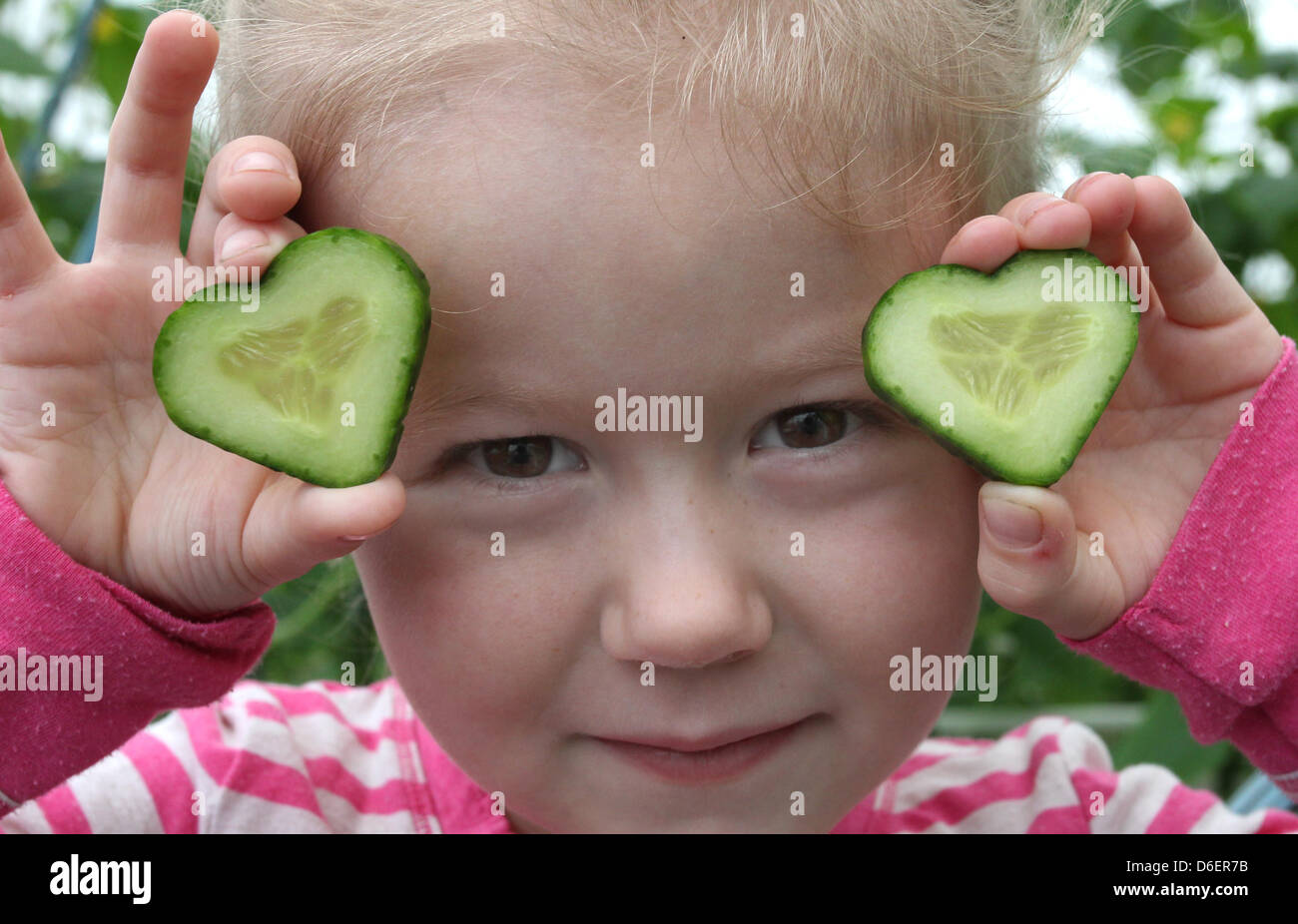 Four-year-old Leni presents two pieces of a heart-shaped cucumber at a ...