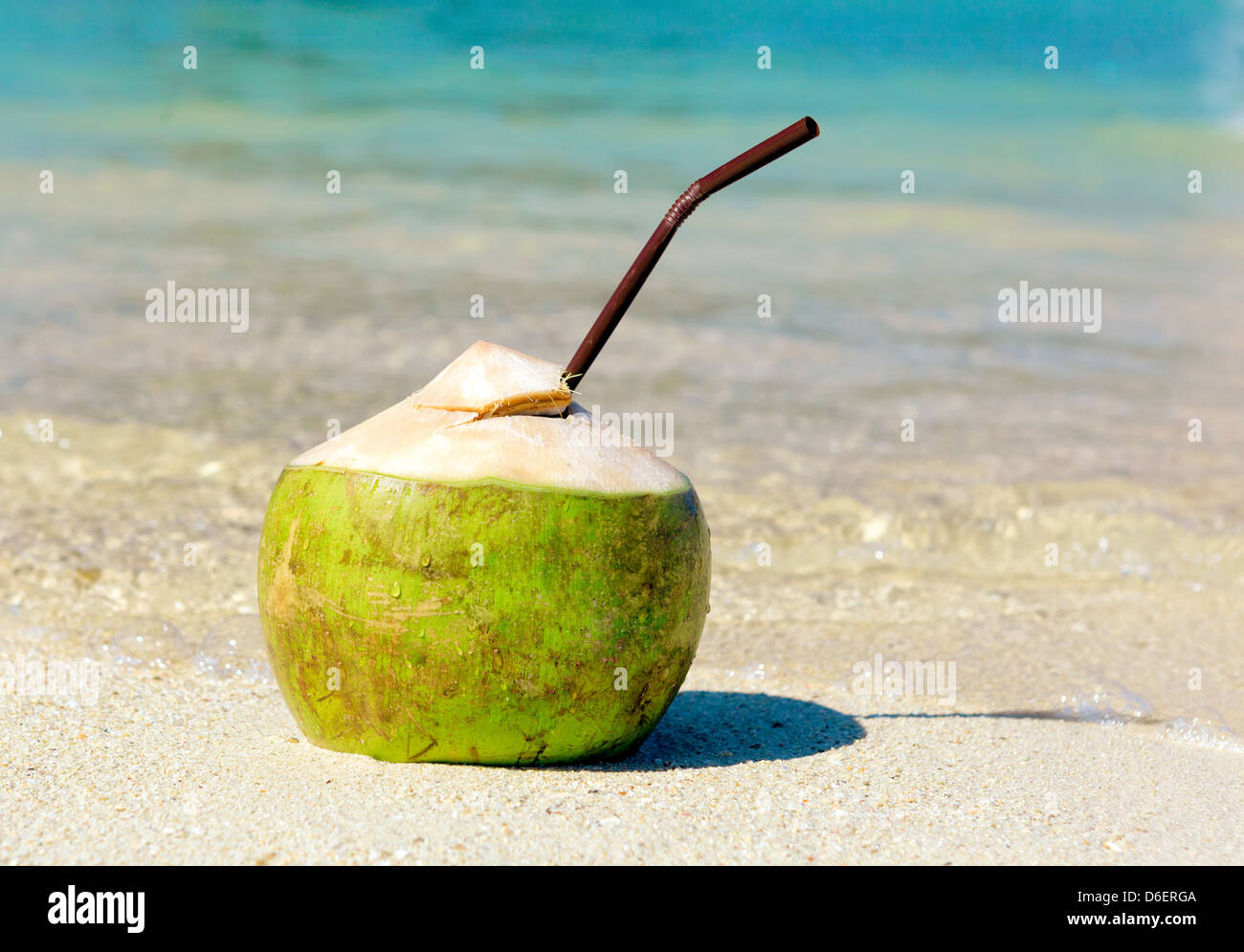 Opened coconut with a straw on summer beach Stock Photo - Alamy