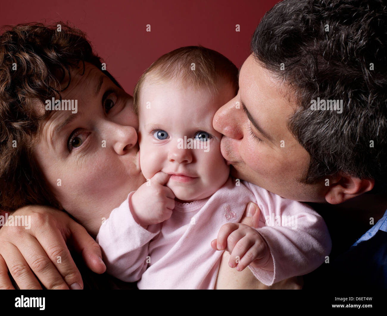Parents kissing baby's cheeks Stock Photo - Alamy