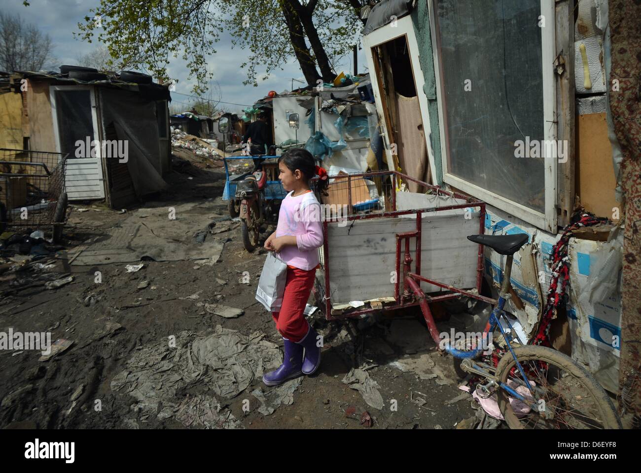 A Roma girl leans against a trailer in front of a makeshift house ...