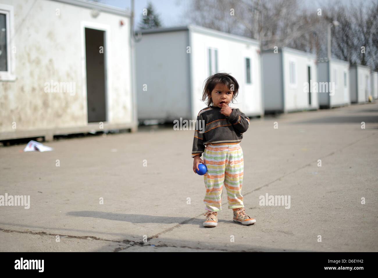 A child stands in front of makeshift housing containers in the Makis ...