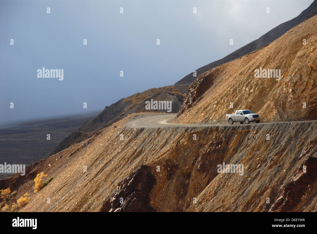 A truck drives on a road with no guard rails and steep cliffs to the ...