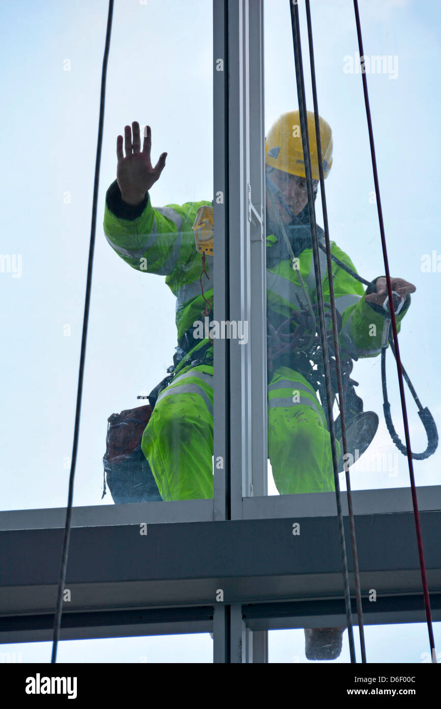 Workman hanging on ropes on external face of a London tower block ...