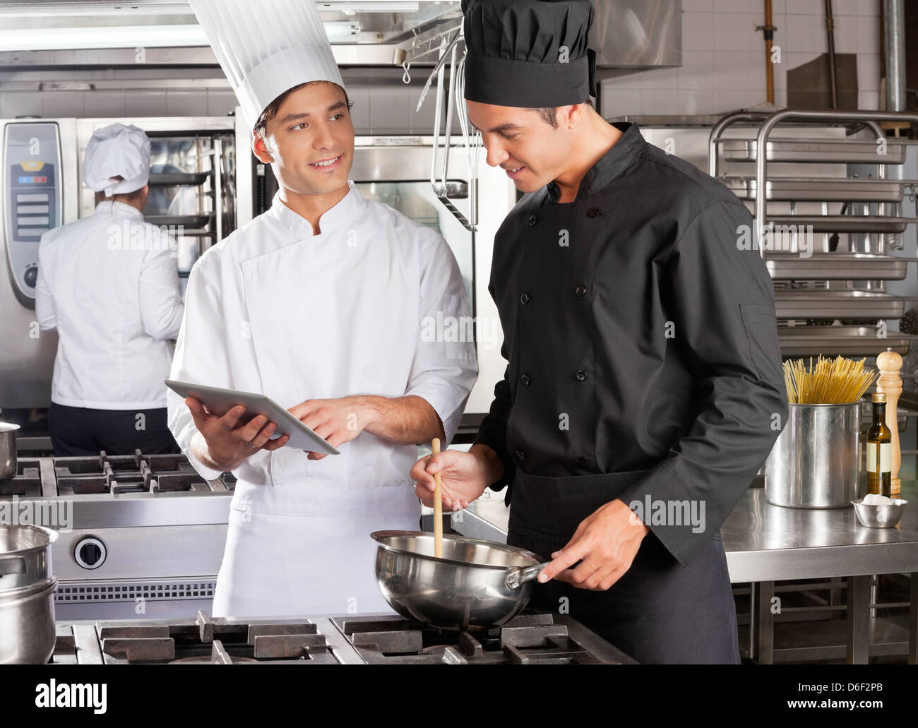 Male Chef Assisting Colleague In Preparing Food Stock Photo - Alamy