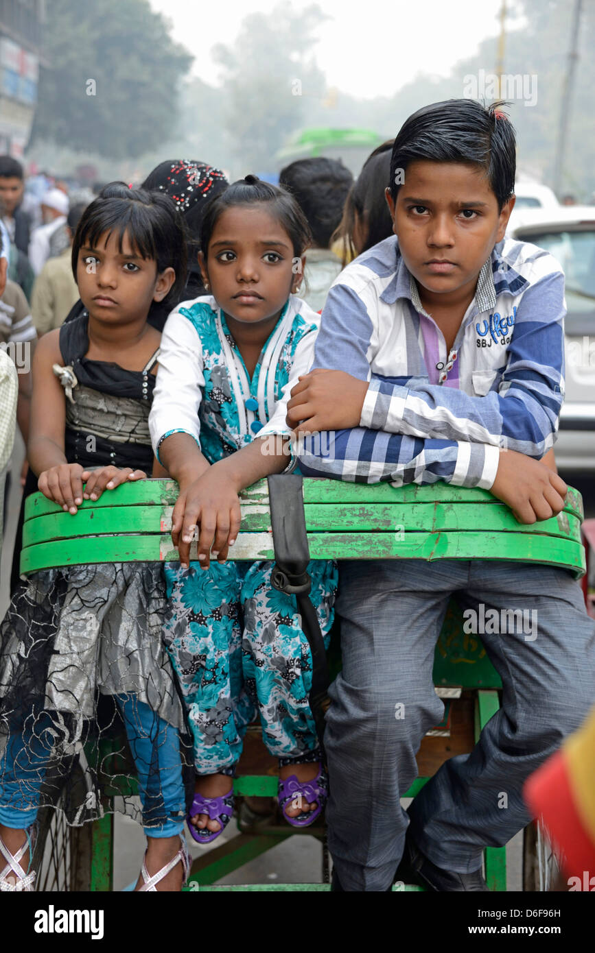 Three children ride on the back of a rickshaw in Old Delhi,India Stock ...