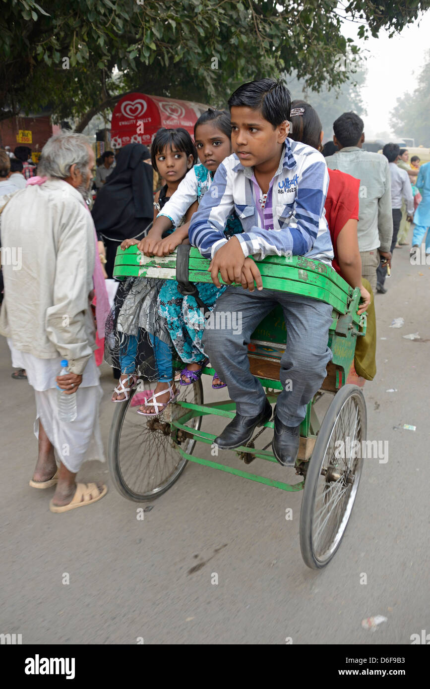 Three children ride on the back of a rickshaw in Old Delhi,India Stock ...