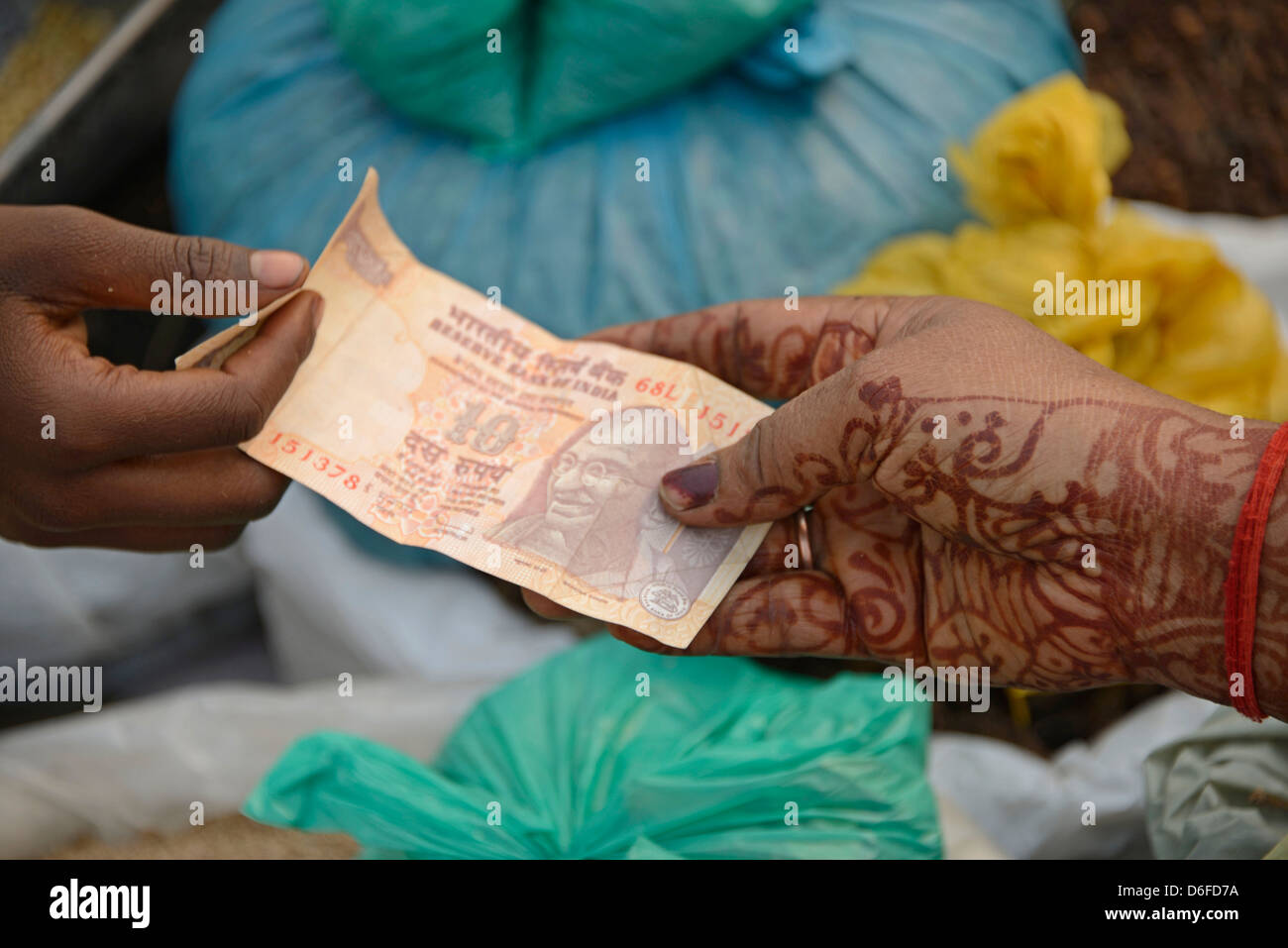 An Indian rupee banknote being exchanged for goods at a market in New ...