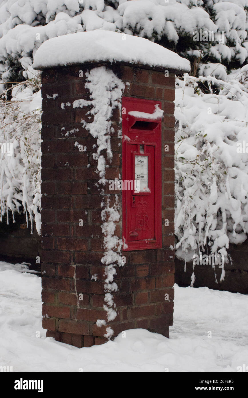 A snow covered post box provides a splash of colour Stock Photo - Alamy