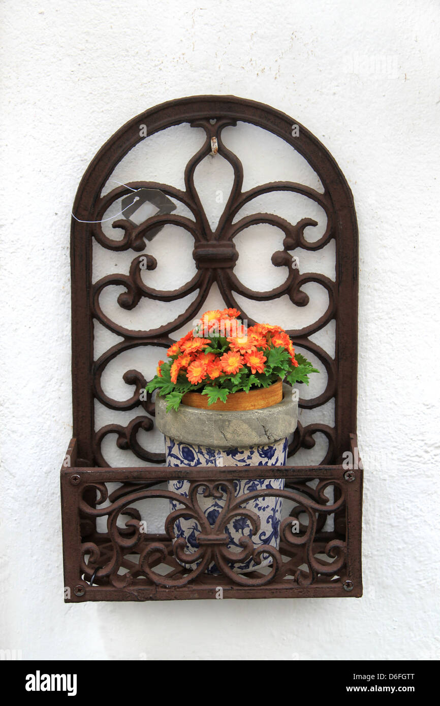 Decorative iron work flower pot holder with orange blossoms on a white ...