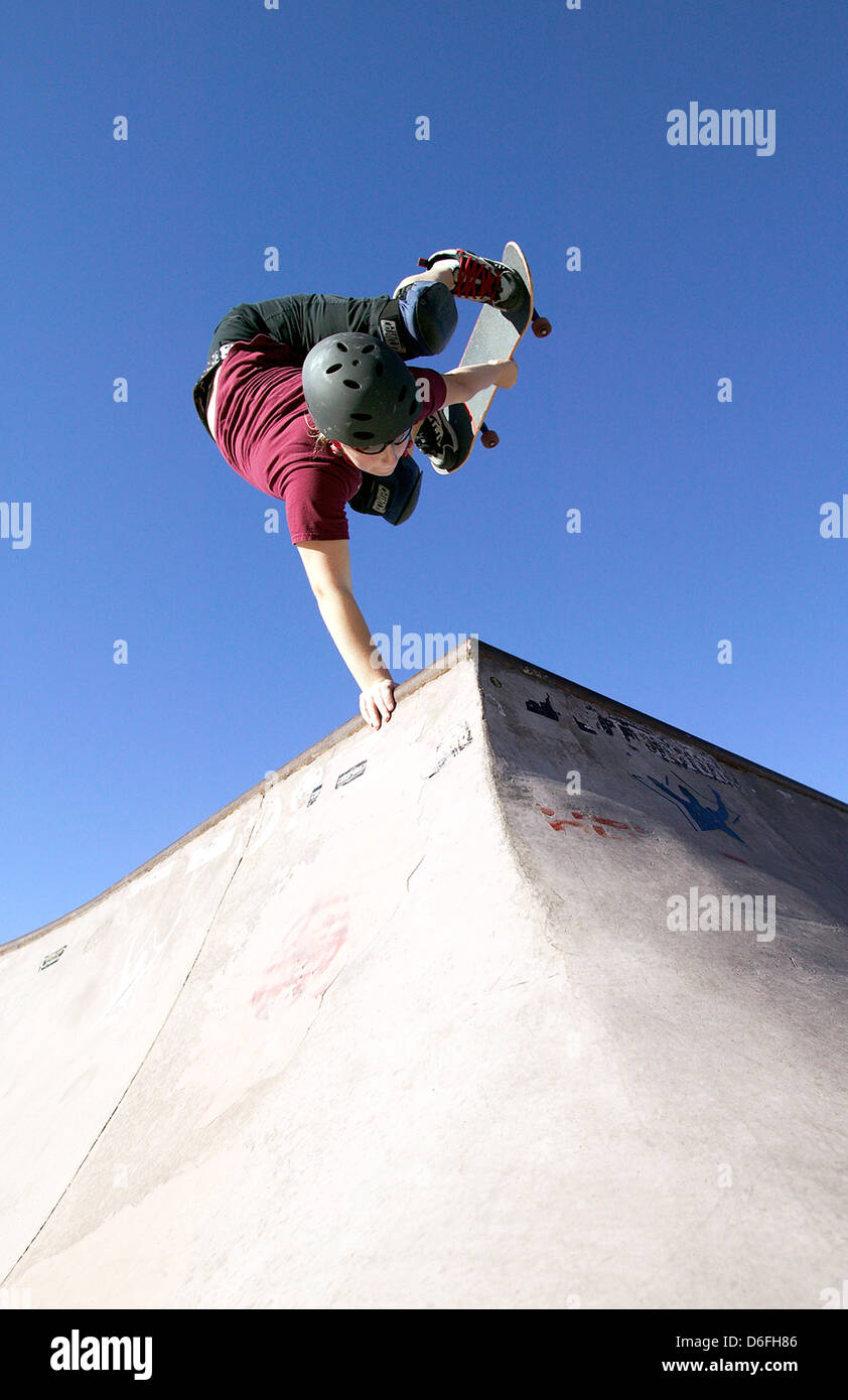 Female teenage girl performs dangerous tricks in a skateboard park ...