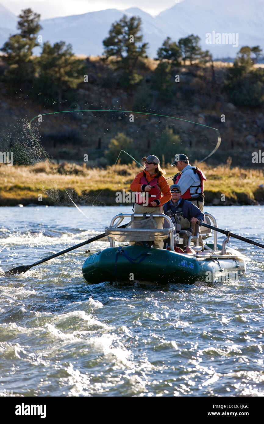 Married couple and professional guide fly fishing from a boat on the ...
