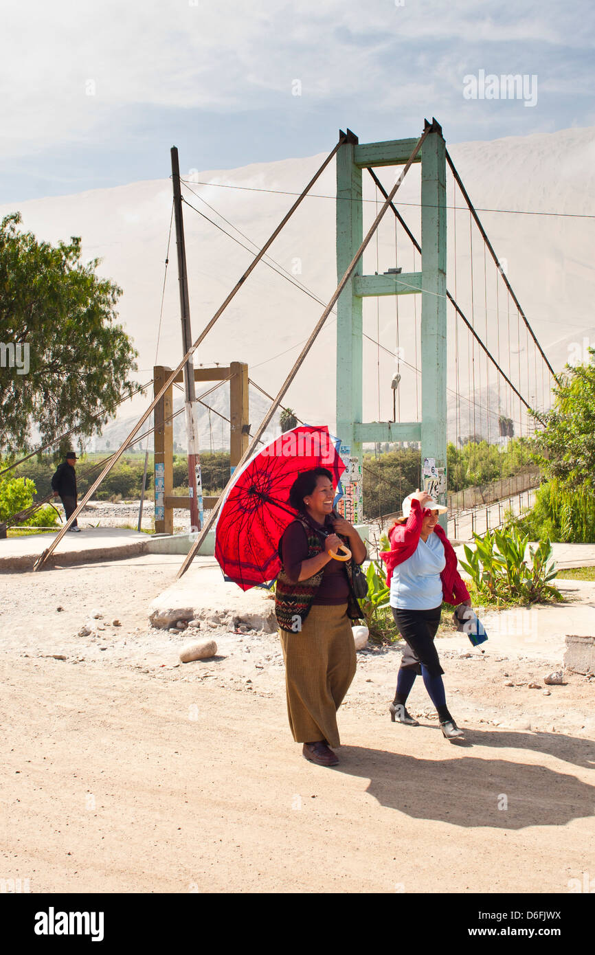 Two women walking in front of a footbridge over Acari River Stock Photo ...