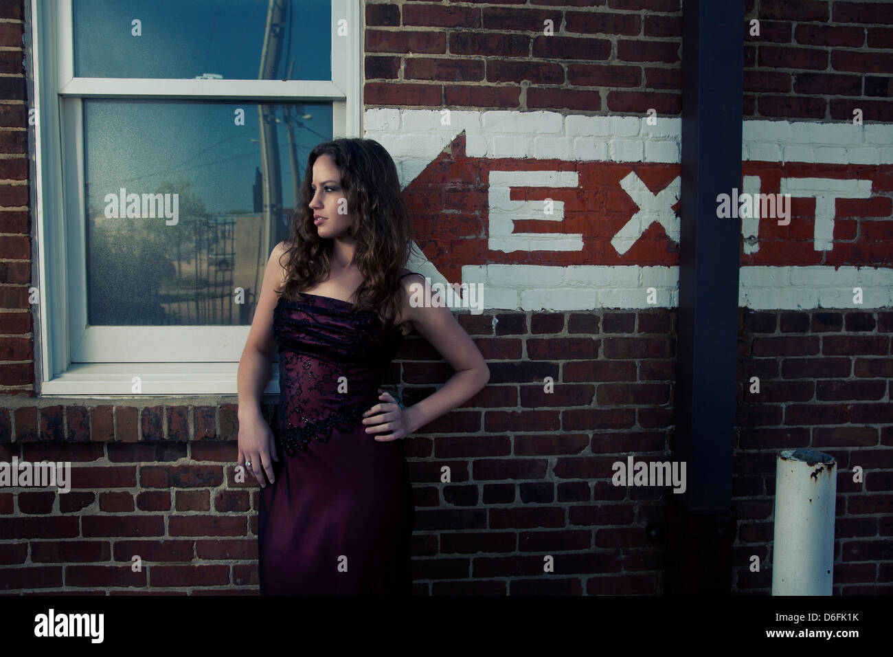 Woman standing against brick wall next to window Stock Photo - Alamy