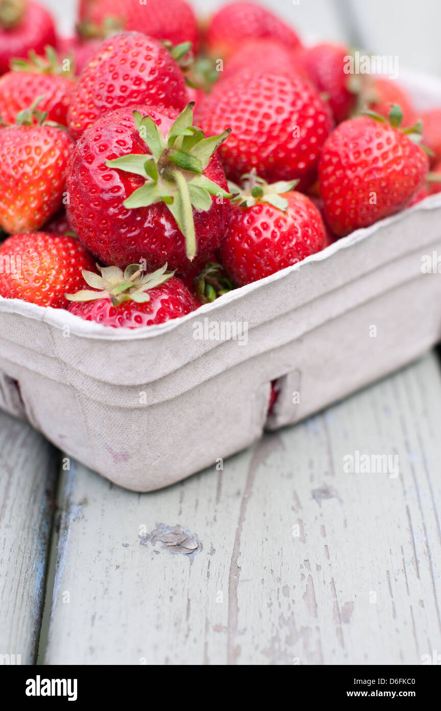 A cardboard carton filled with fresh picked ripe red strawberries, on a ...