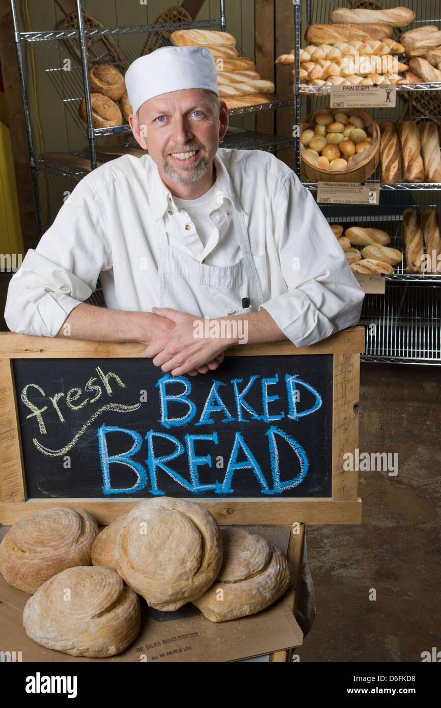 Portrait of professional cook in his bakery, surrounded by fresh baked ...