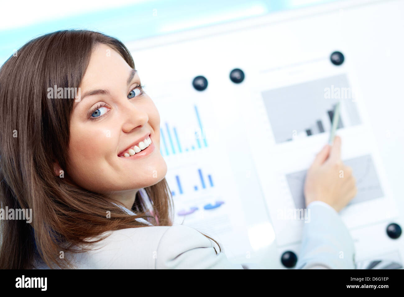 Portrait of a lovely young businesswoman looking at camera while ...