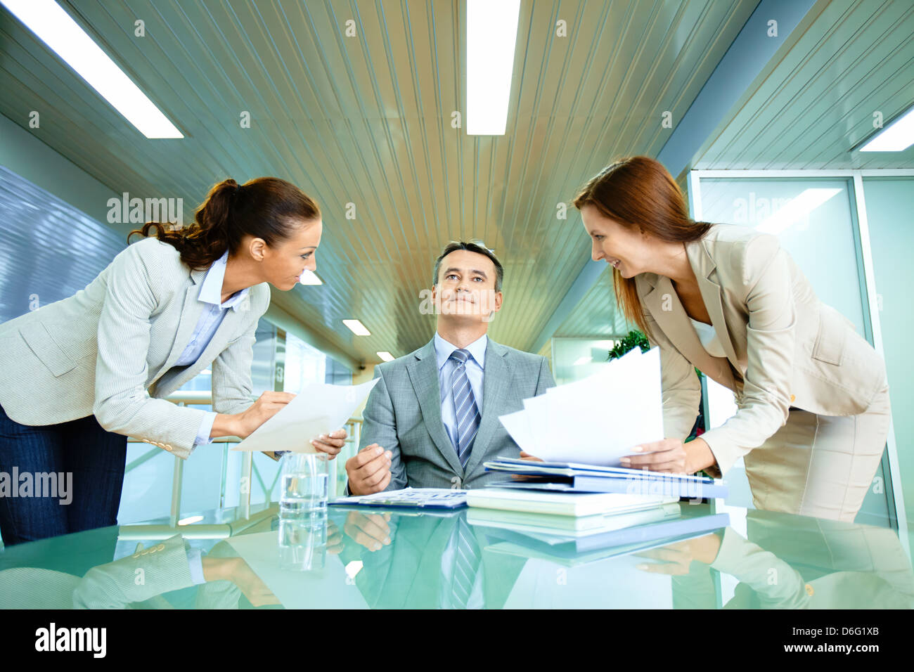 Inspirated boss sitting at workplace surrounded by two secretaries ...