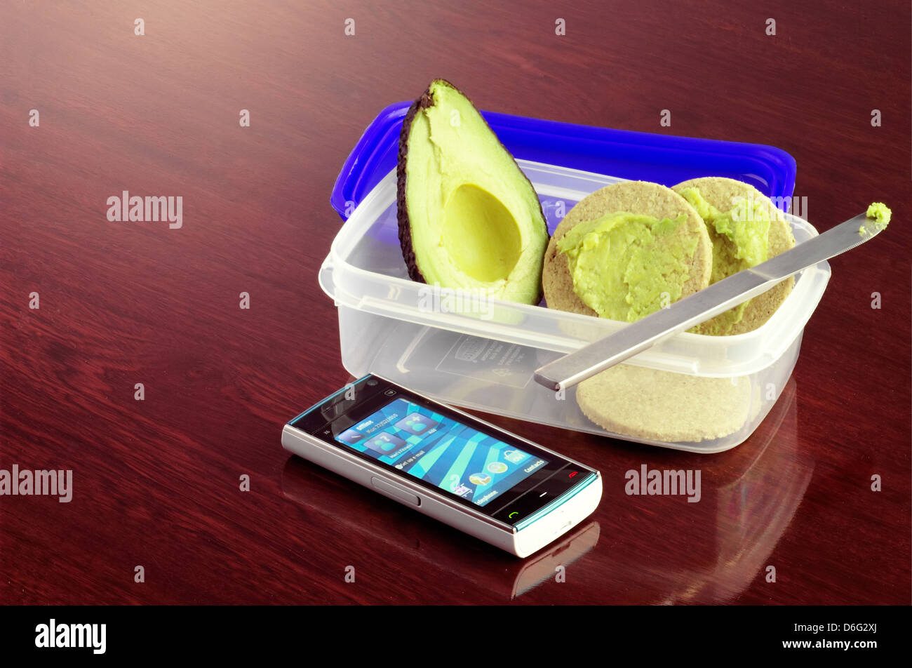 Avocado and Oatcakes snack at work with mobile phone Stock Photo - Alamy