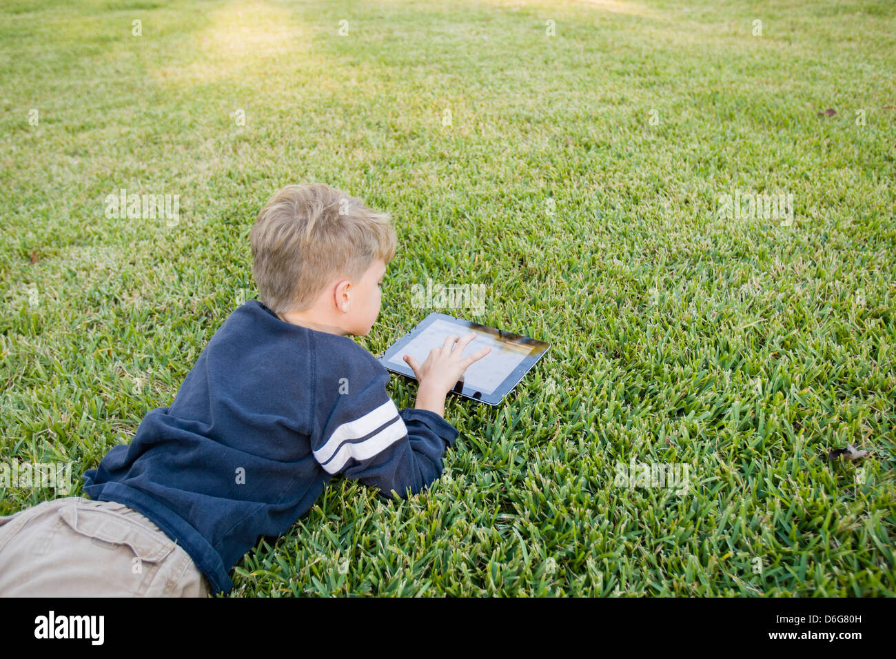 Caucasian boy using digital tablet on lawn Stock Photo - Alamy
