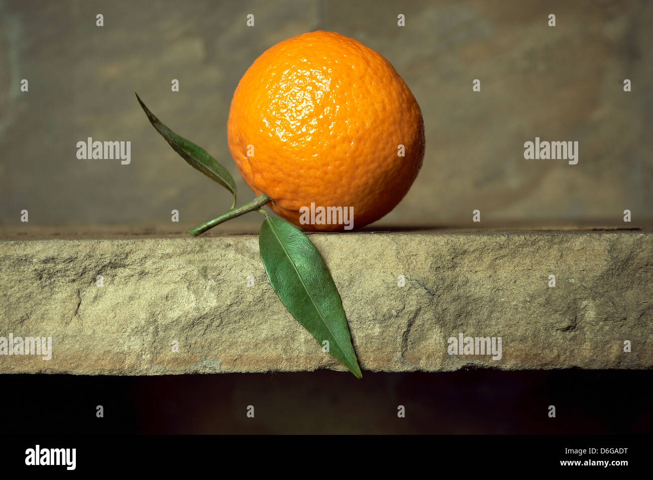 Single orange with leaves on stone background Stock Photo - Alamy