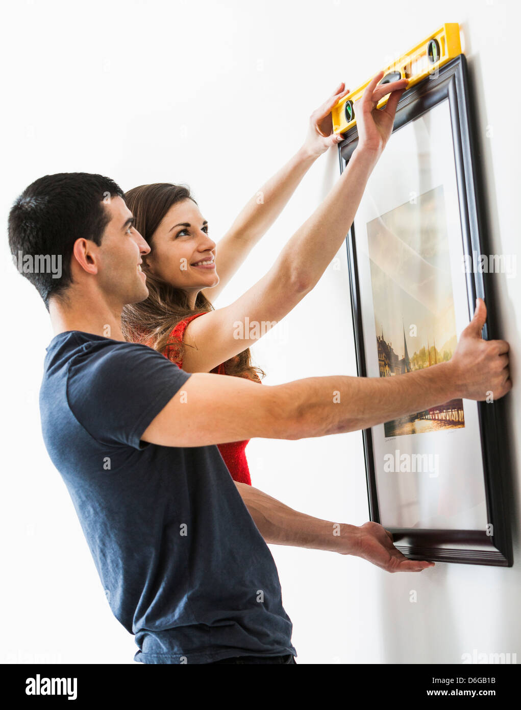 Couple measuring picture frame on wall Stock Photo - Alamy
