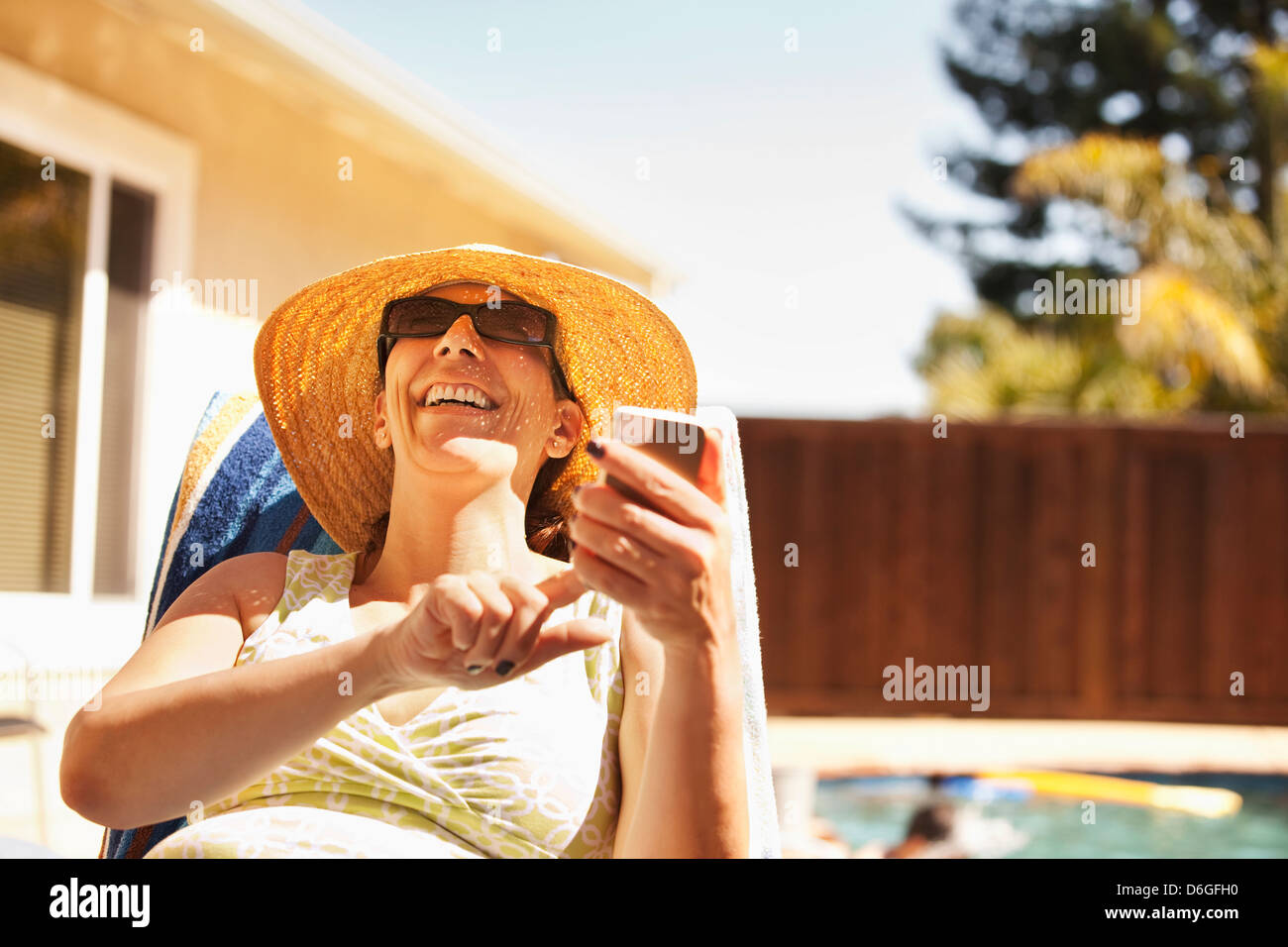 Hispanic woman using cell phone by pool Stock Photo - Alamy