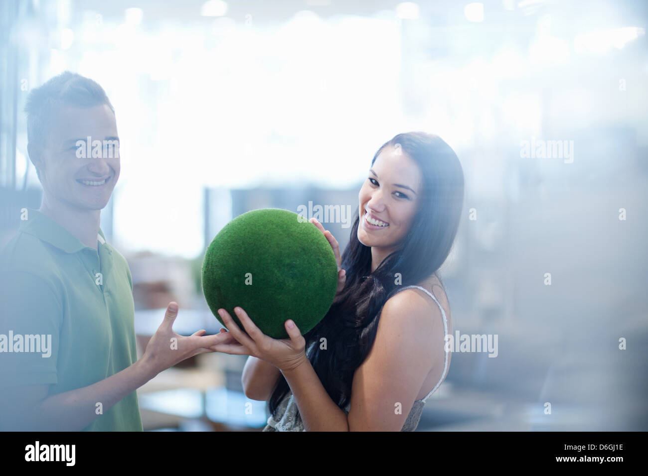 Smiling couple holding green ball Stock Photo - Alamy