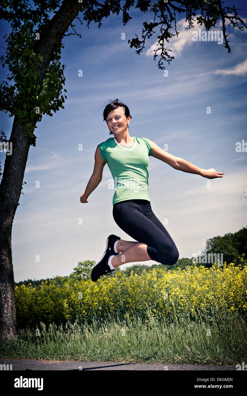 a young jumping woman in front of rural landscape Stock Photo - Alamy