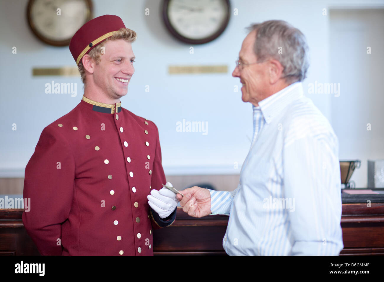 Older man tipping bellhop in lobby Stock Photo - Alamy