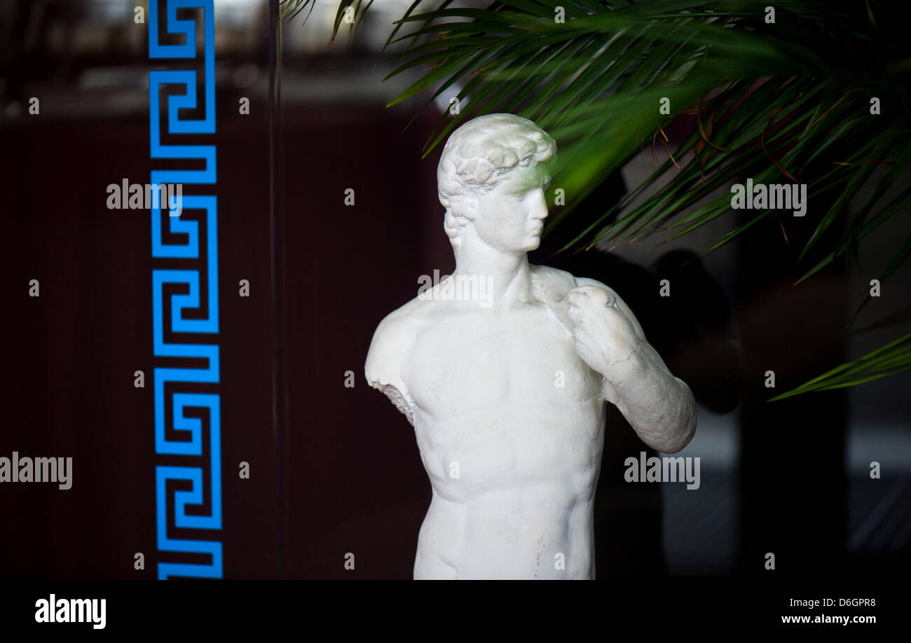 A male statue missing an arm is pictured in front of a Greek restaurant ...