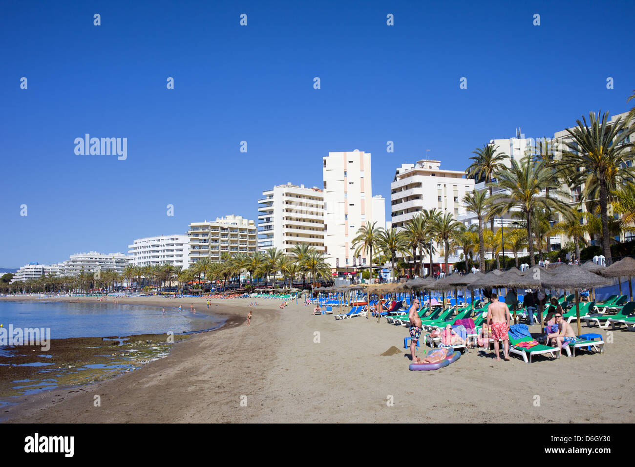 Sun loungers and tourists on a sandy beach at the popular resort of ...