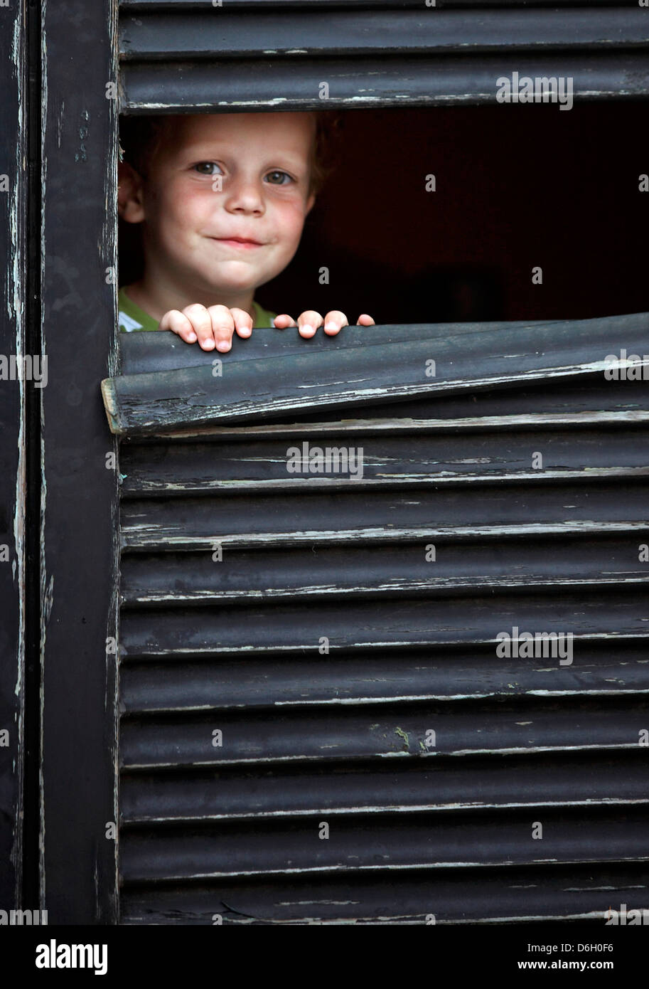 Toddler boy peeking out from window Stock Photo - Alamy
