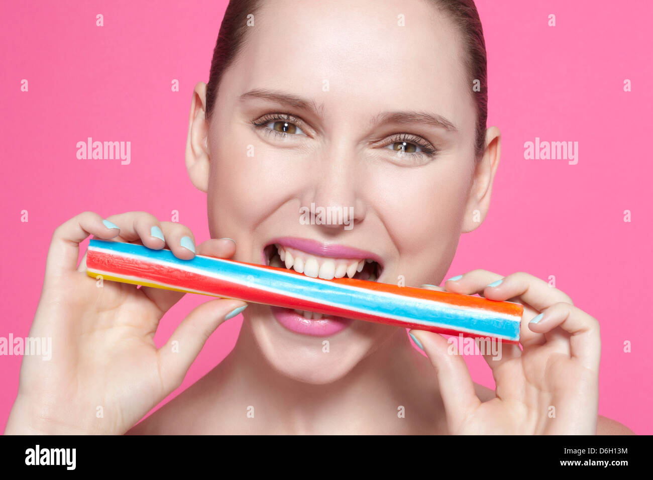 Smiling woman biting candy Stock Photo - Alamy