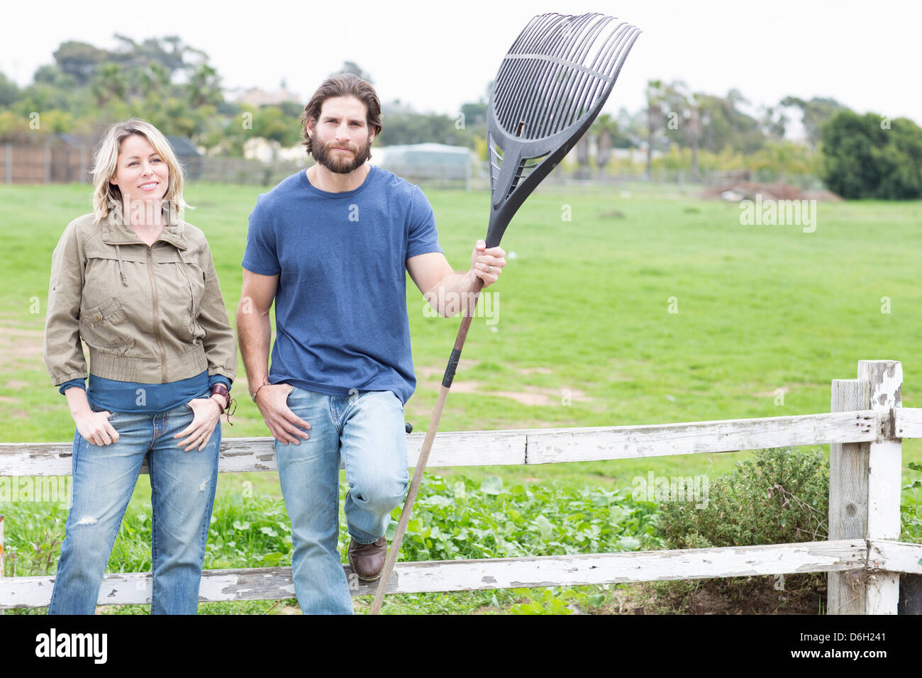 Couple leaning on wooden fence Stock Photo - Alamy