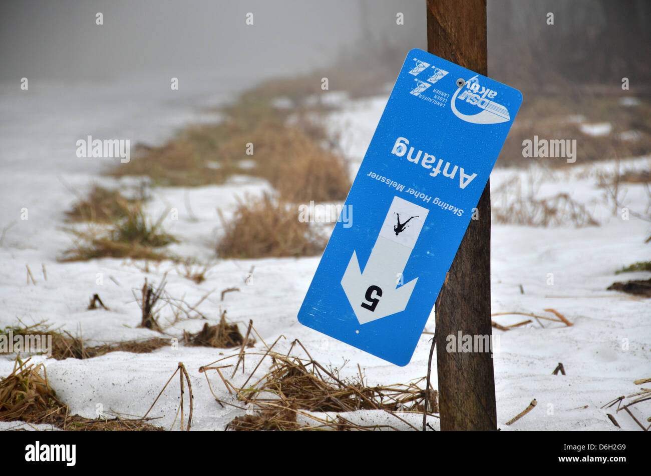 A cross country skiing sign stands in a field with the remnants of snow ...