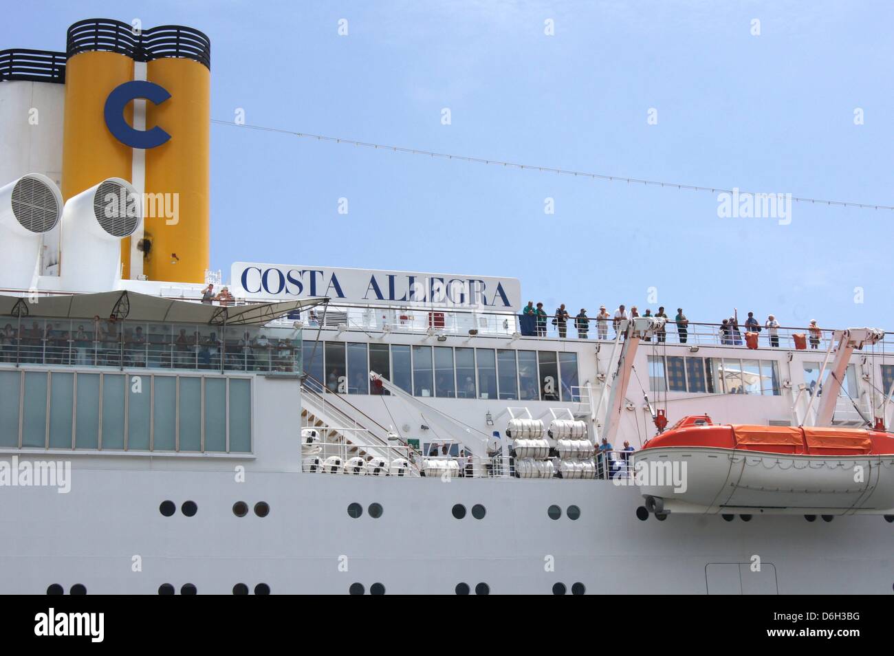 Passengers stand on board during the arrival of the Costa Allegra ...
