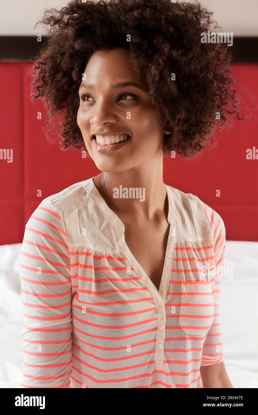 Smiling woman sitting on bed Stock Photo - Alamy