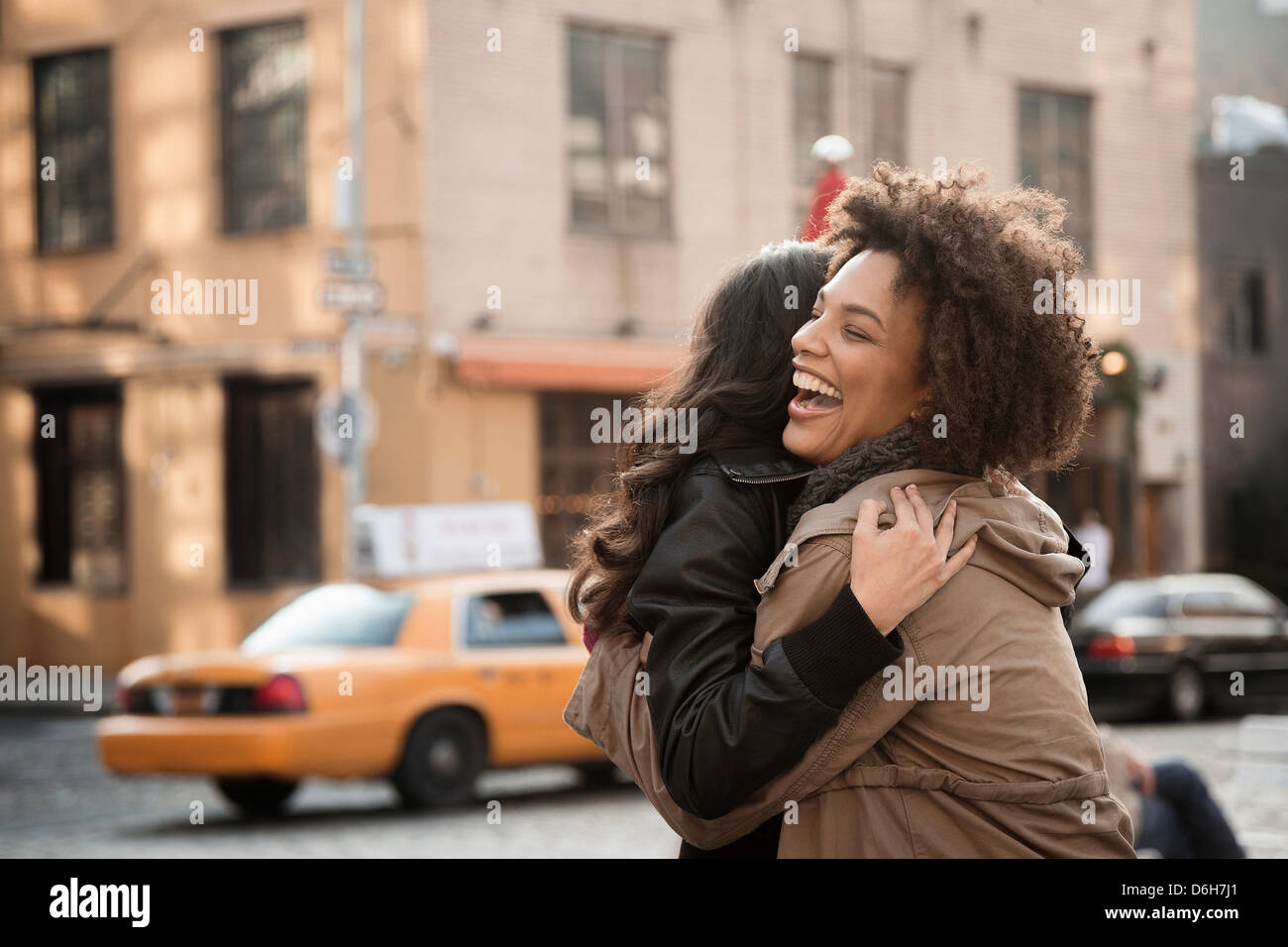 Women hugging on city street Stock Photo - Alamy