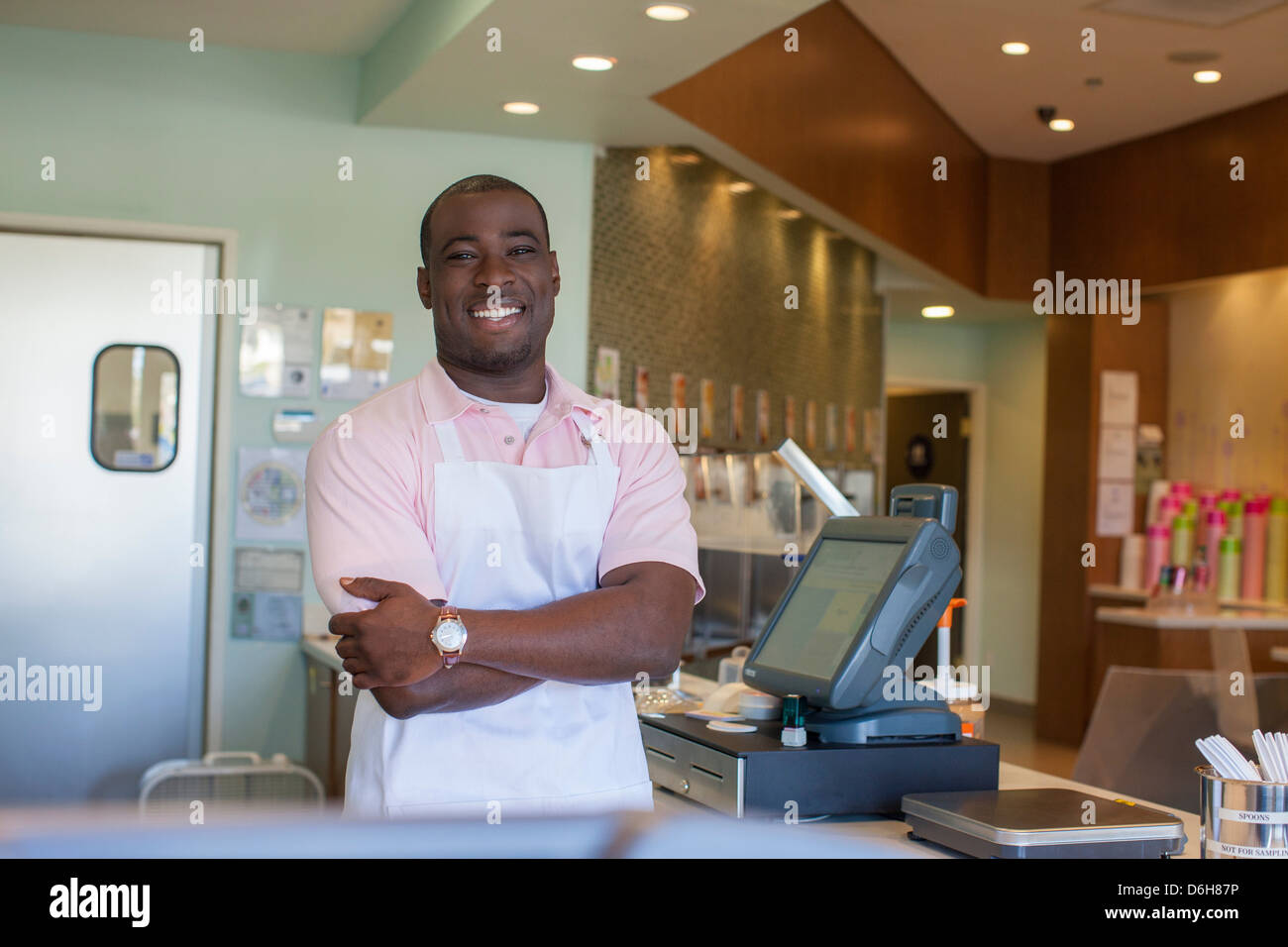 Cashier smiling behind counter Stock Photo - Alamy