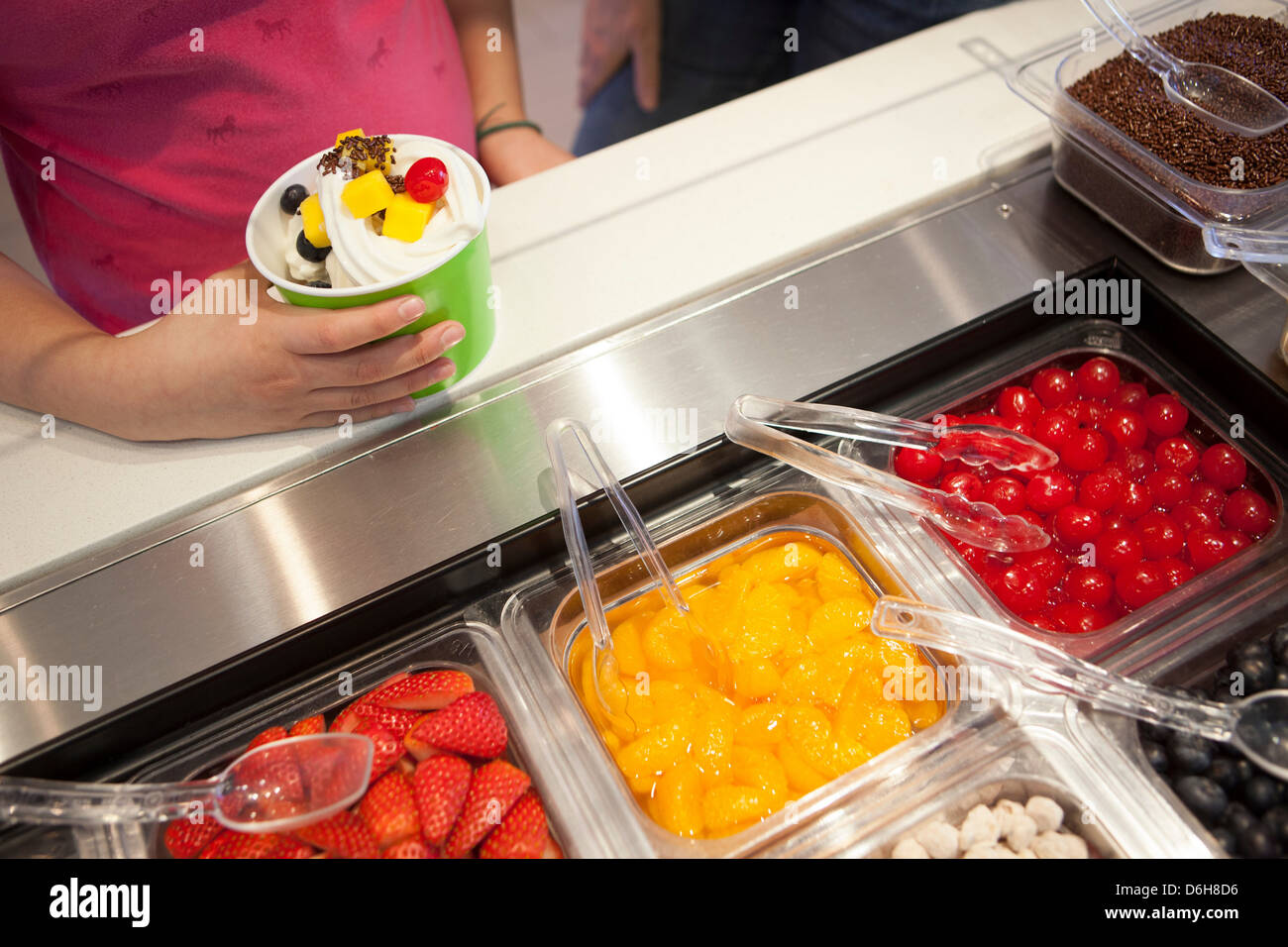 Girl putting toppings on frozen yogurt Stock Photo - Alamy