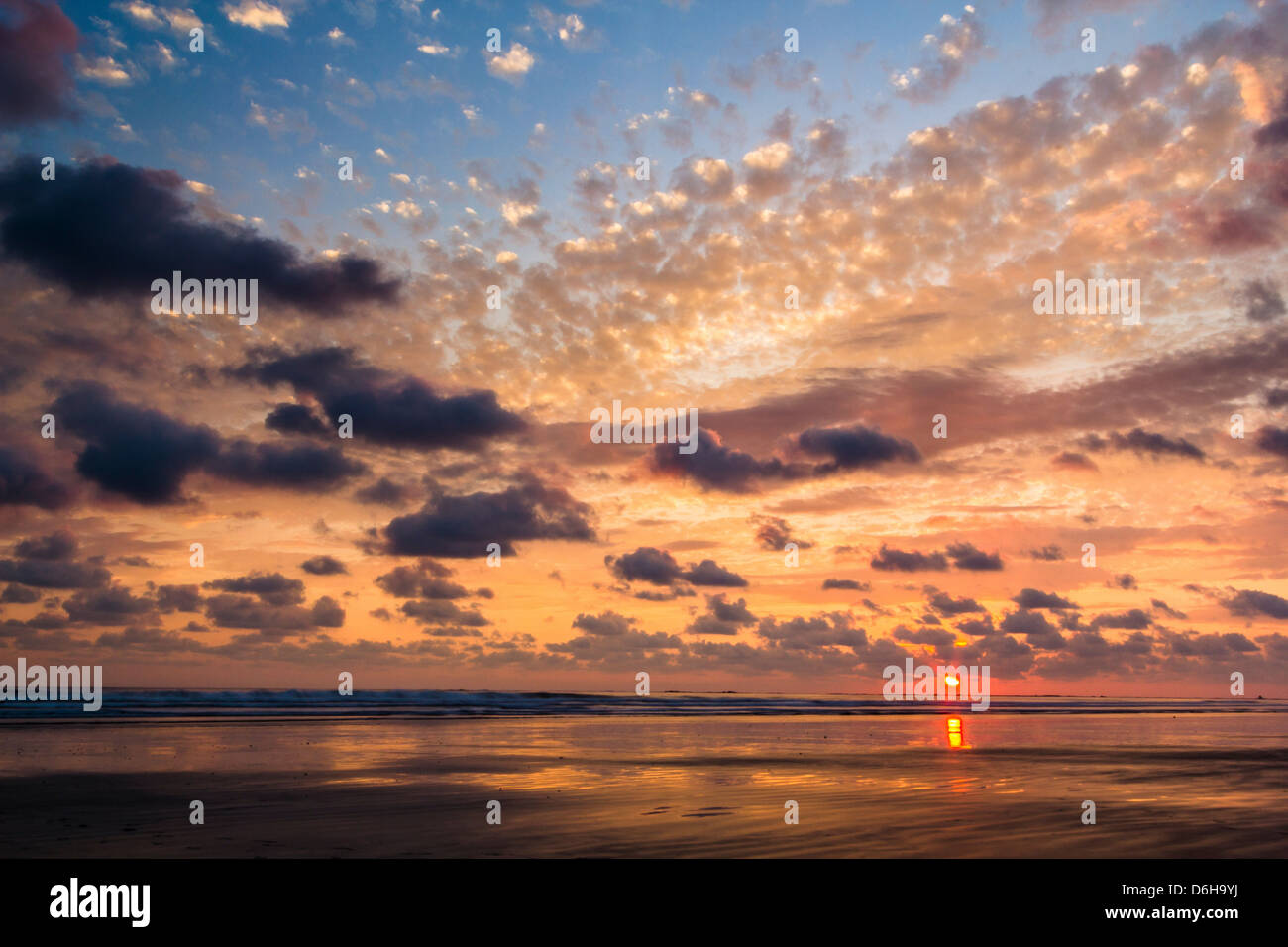 Sun setting over water in dramatic sky Stock Photo - Alamy