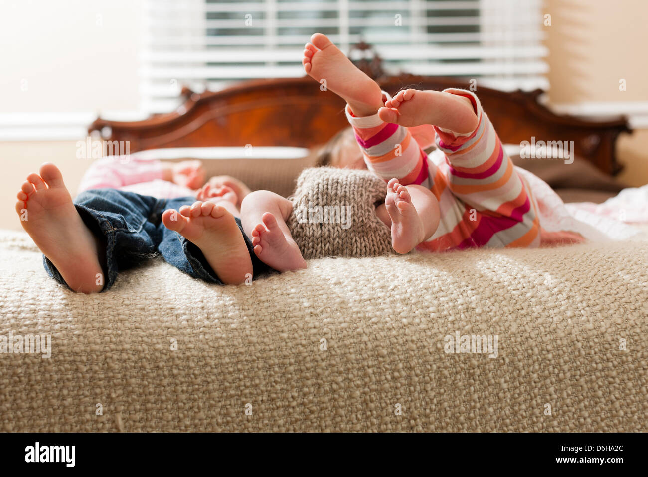 Children laying with infant on bed Stock Photo - Alamy