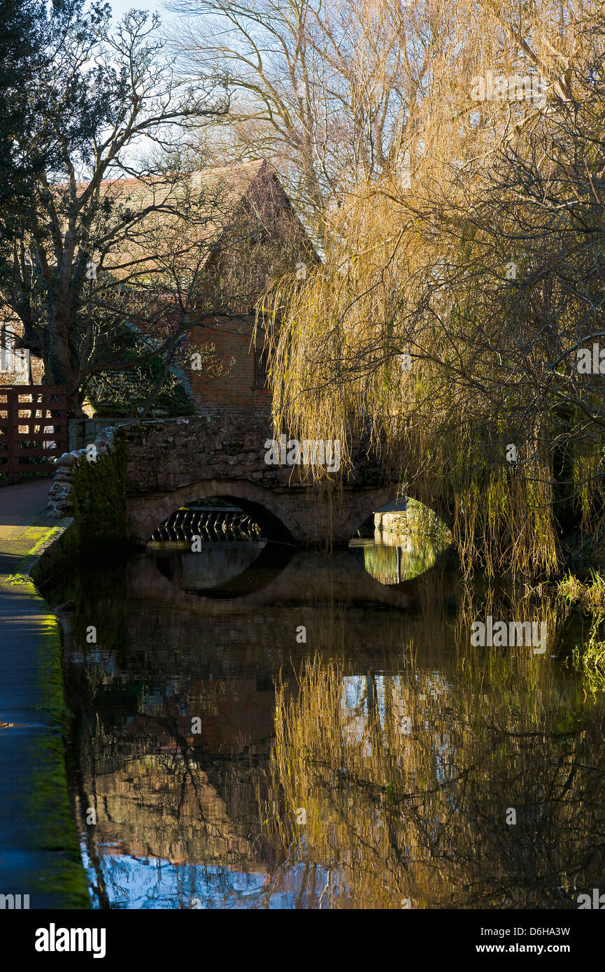 Mill stream, water mill and bridge with willow trees and calm ...