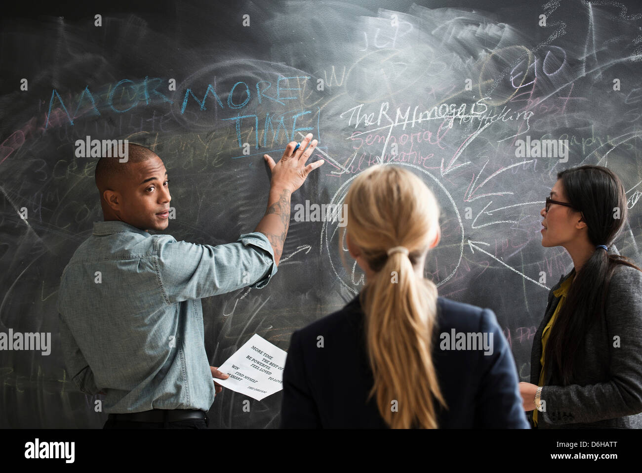 Man writing on blackboard, colleagues watching Stock Photo - Alamy