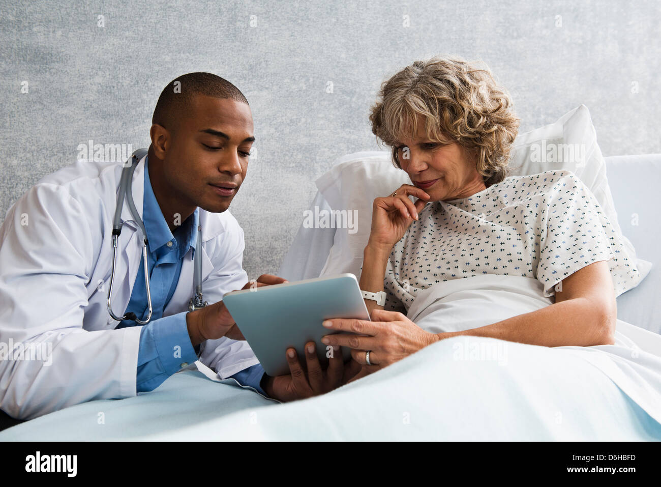Doctor showing digital tablet to patient in hospital Stock Photo - Alamy