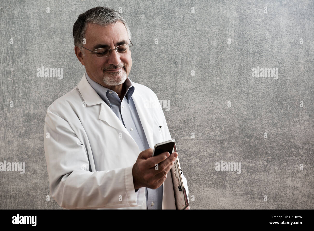 Male doctor looking at cellphone Stock Photo - Alamy