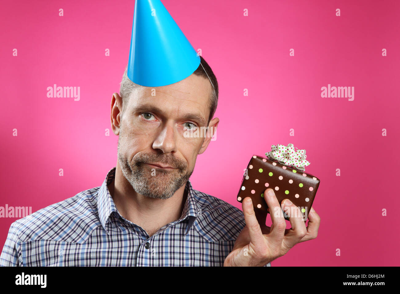Man in party hat with a disappointed expression holding a gift Stock ...