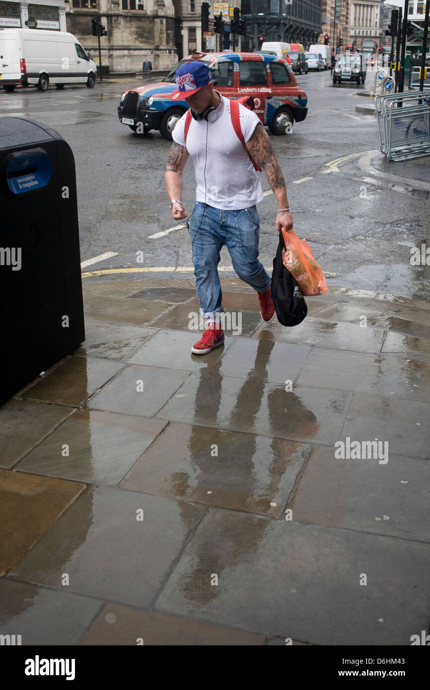 A man with tattooed arms dashes through seasonal rain showers in ...