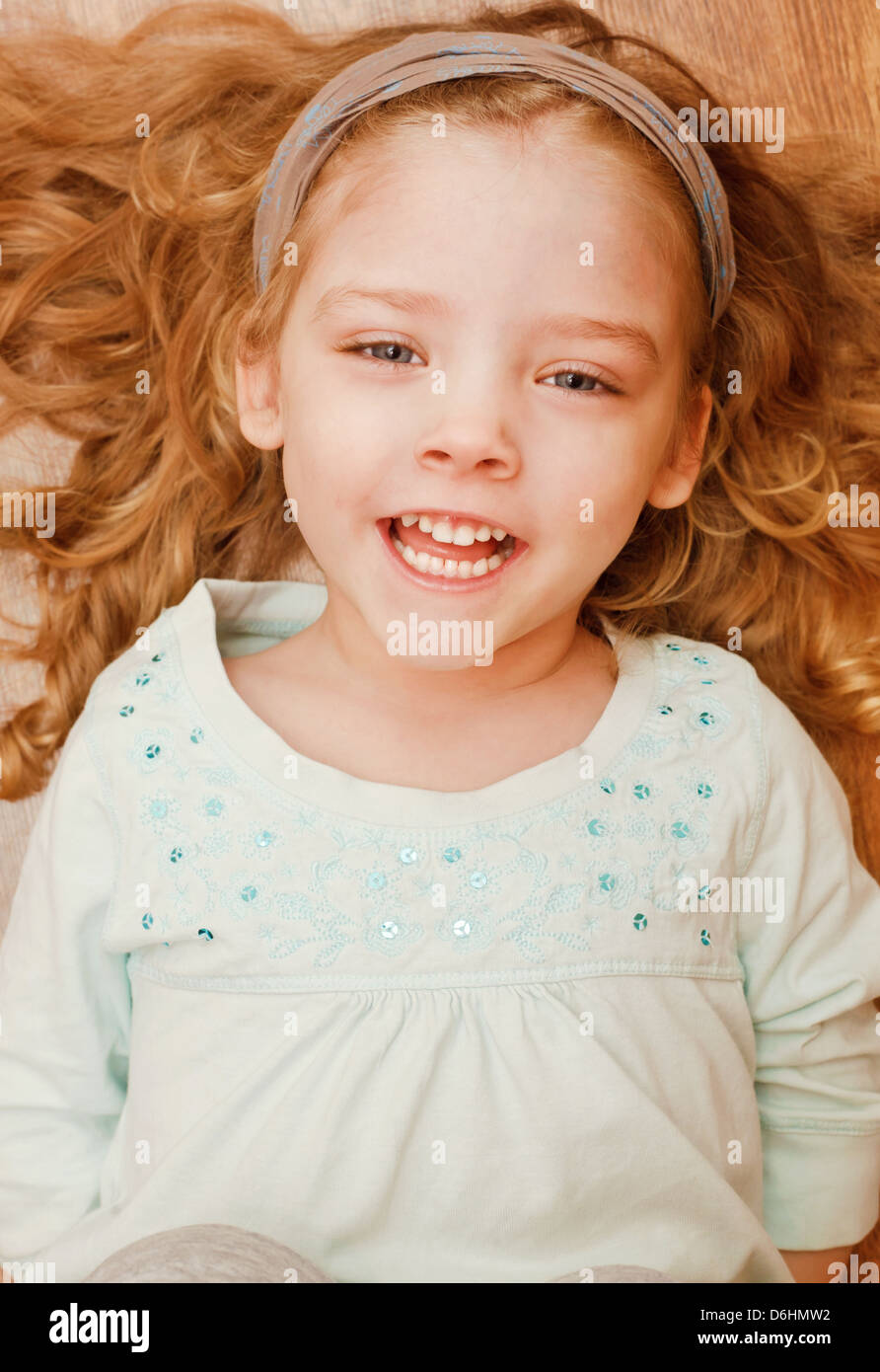 Happy little girl lying on floor Stock Photo - Alamy