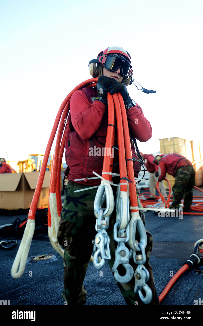 A US Navy sailor carries cargo hooks on the flight deck of the aircraft ...
